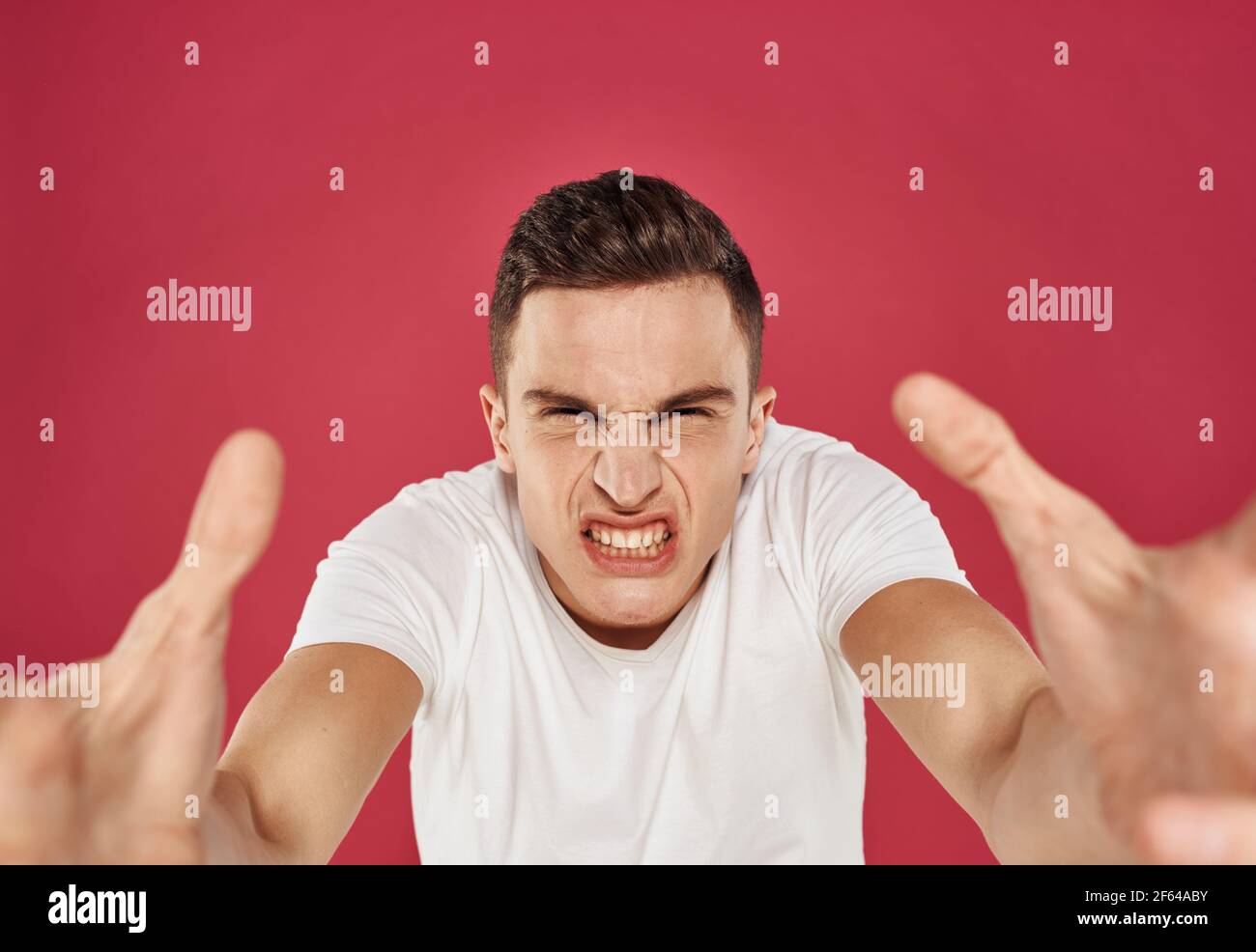 emotional man angry facial expression white t-shirt red background ...