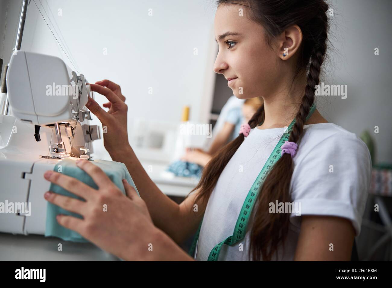 Adorable girl using modern sewing machine in workshop Stock Photo - Alamy