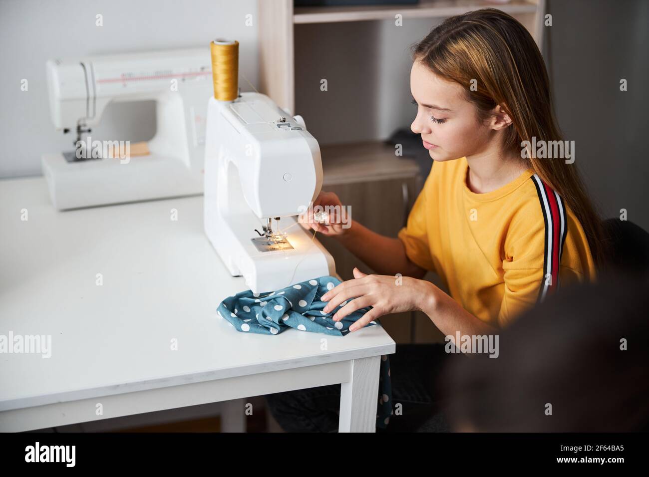 Cute girl seamstress sewing fabric in workshop Stock Photo - Alamy