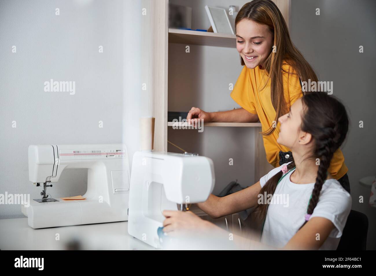 Cute female children sewing clothes in workshop Stock Photo - Alamy