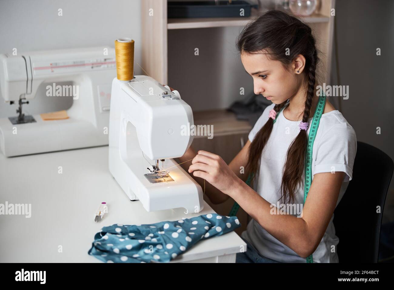 Cute girl sewing clothes in dressmaking studio Stock Photo - Alamy