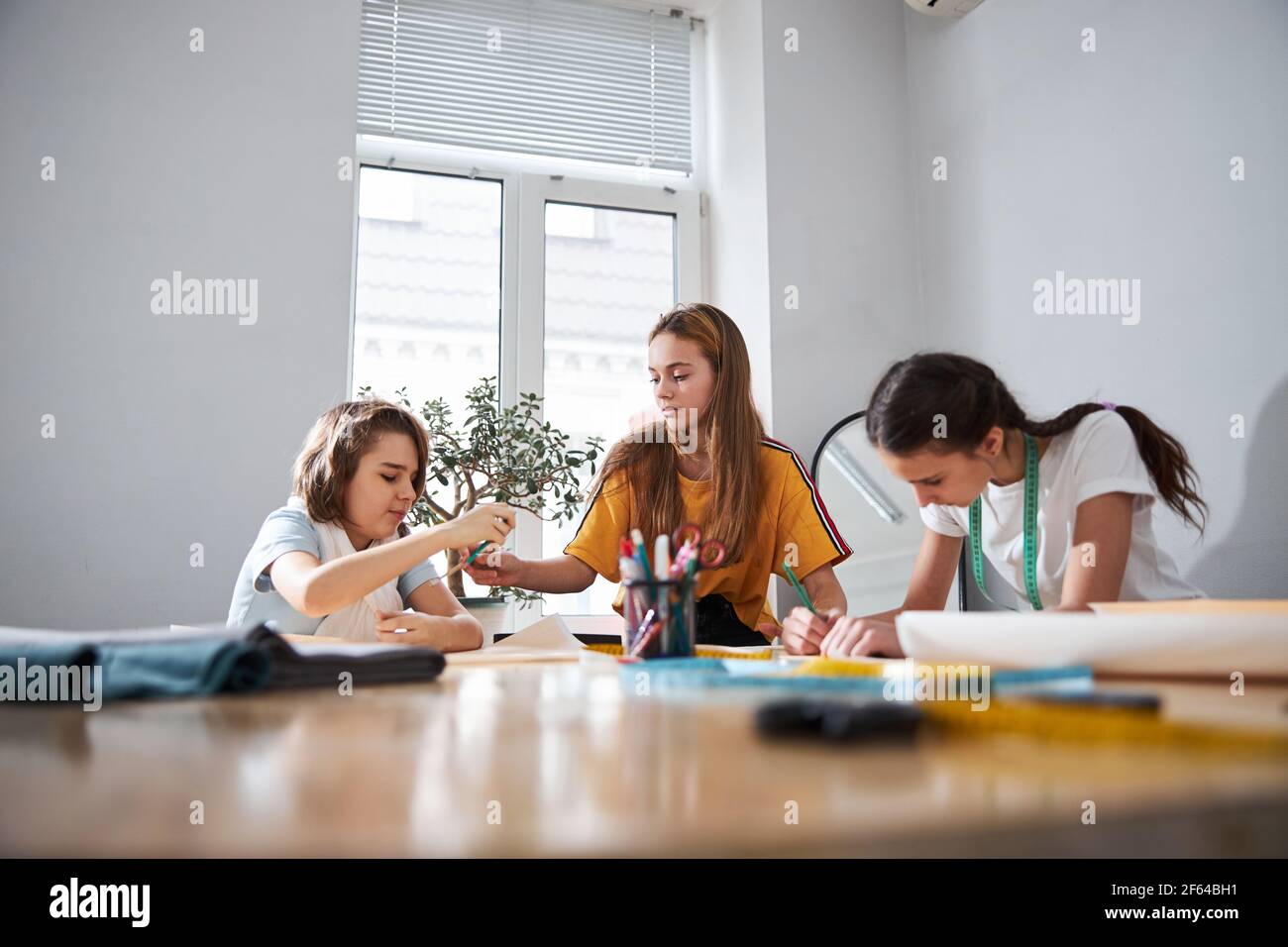 Adorable female children making sewing patterns in workshop Stock Photo ...