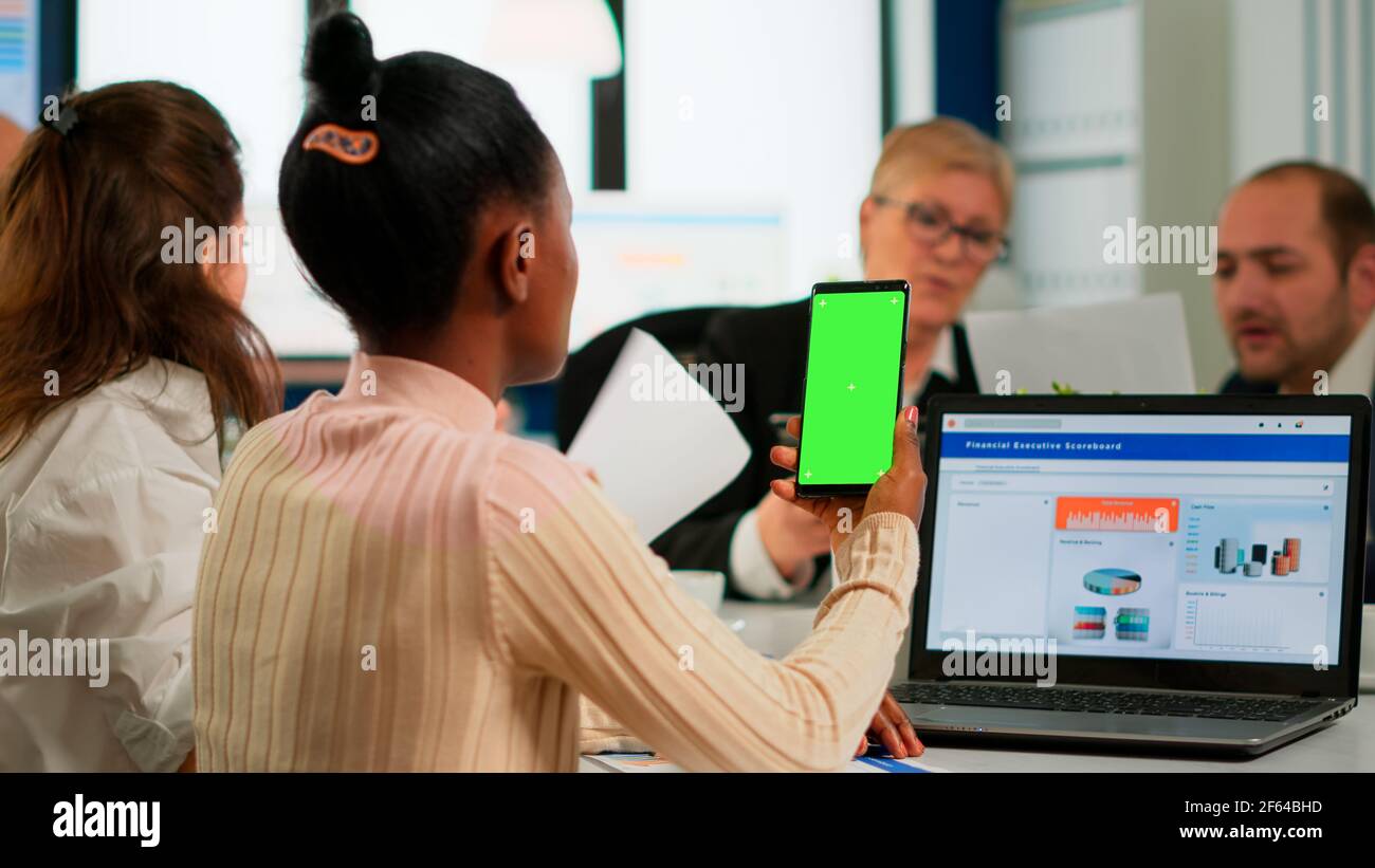 Back view of black businesswoman sitting at conference desk holding ...