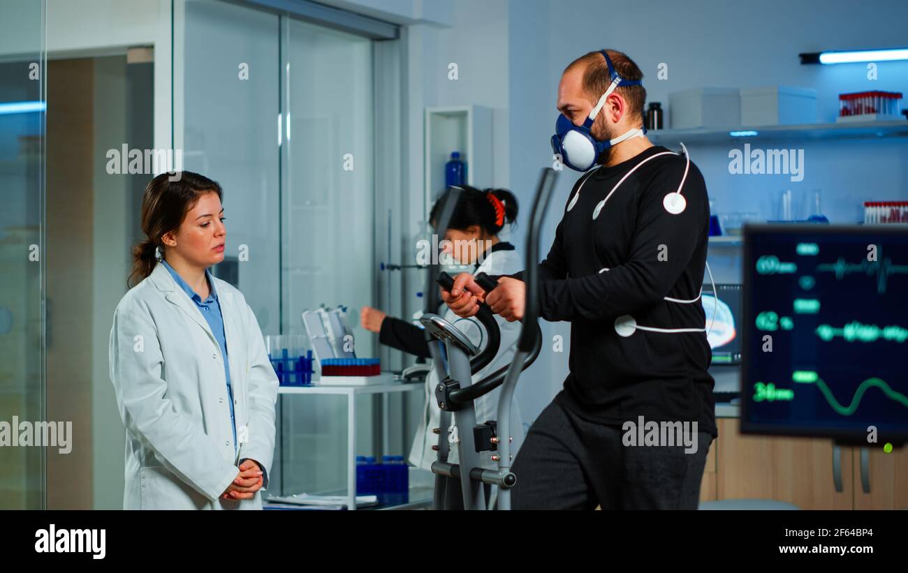 Sportsman running on cross trainer in lab facility for sports ...