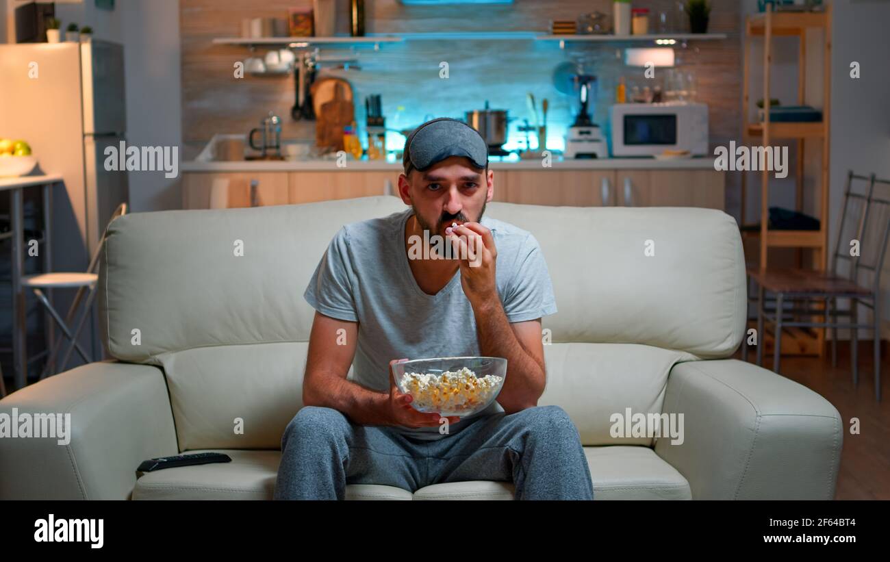 Concentrated man with sleep eye mask sitting in front of television ...