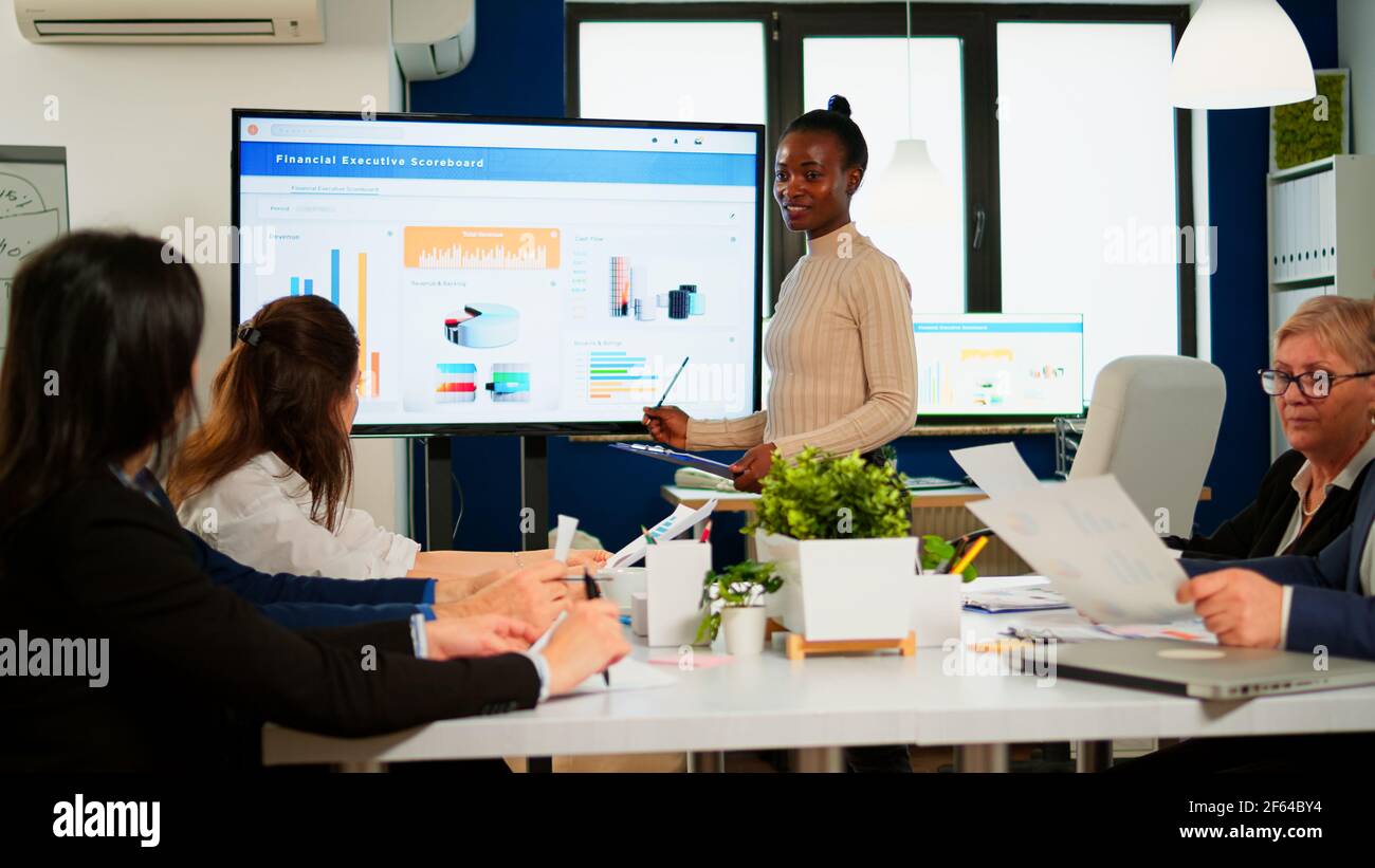 Black woman worker explaning company statistics in front of colleagues ...