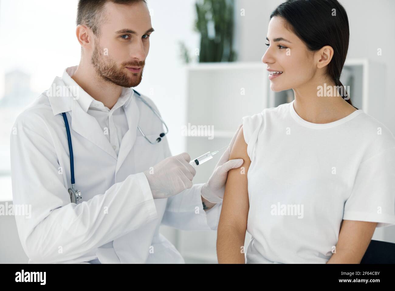 male doctor with syringe in hand and female patient injection vaccine ...