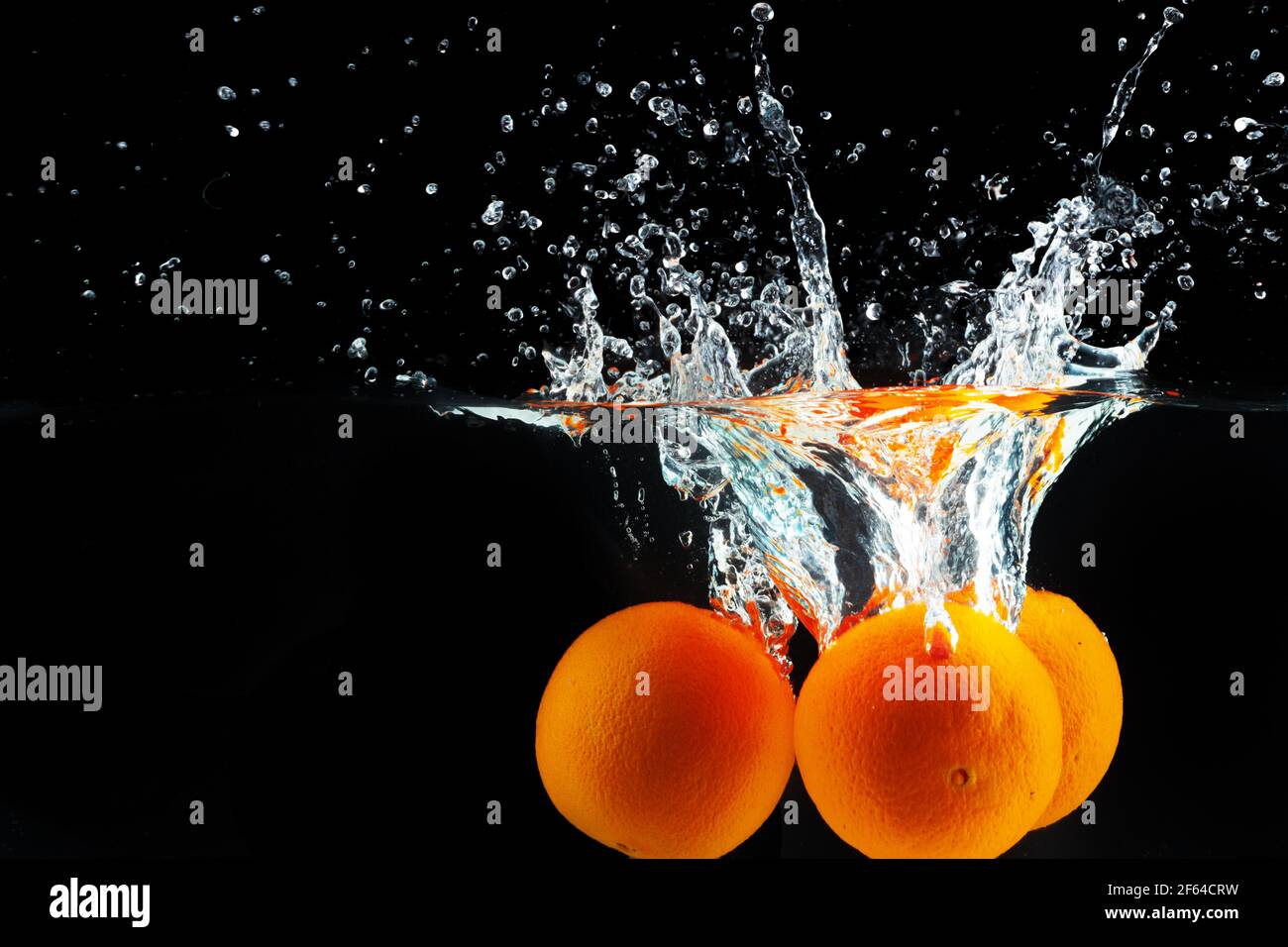 Oranges falling into water against black background, studio shot Stock ...
