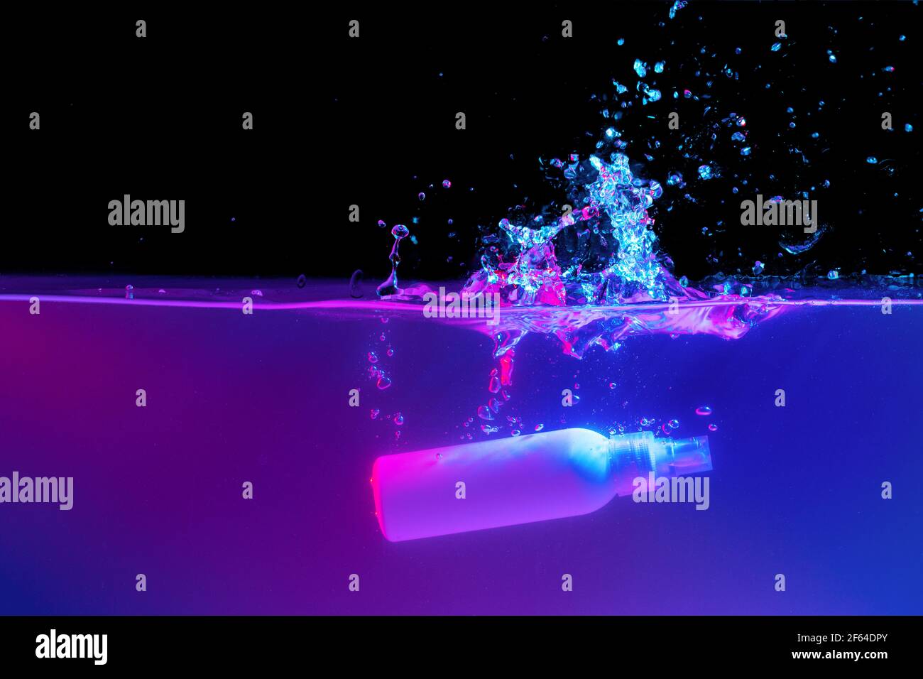Skincare product bottle falling into water against black background in ...