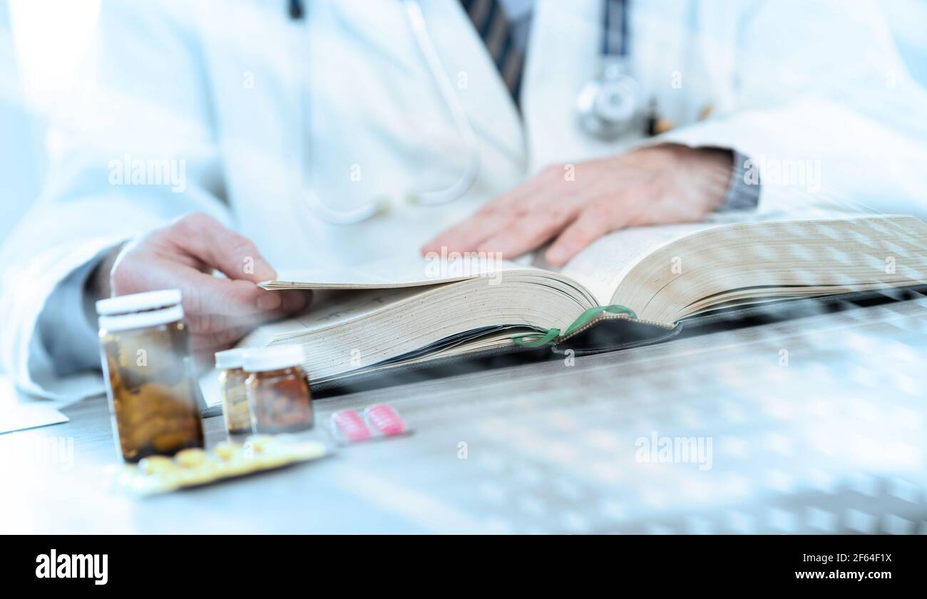 Doctor reading a textbook in medical office; light effect Stock Photo ...