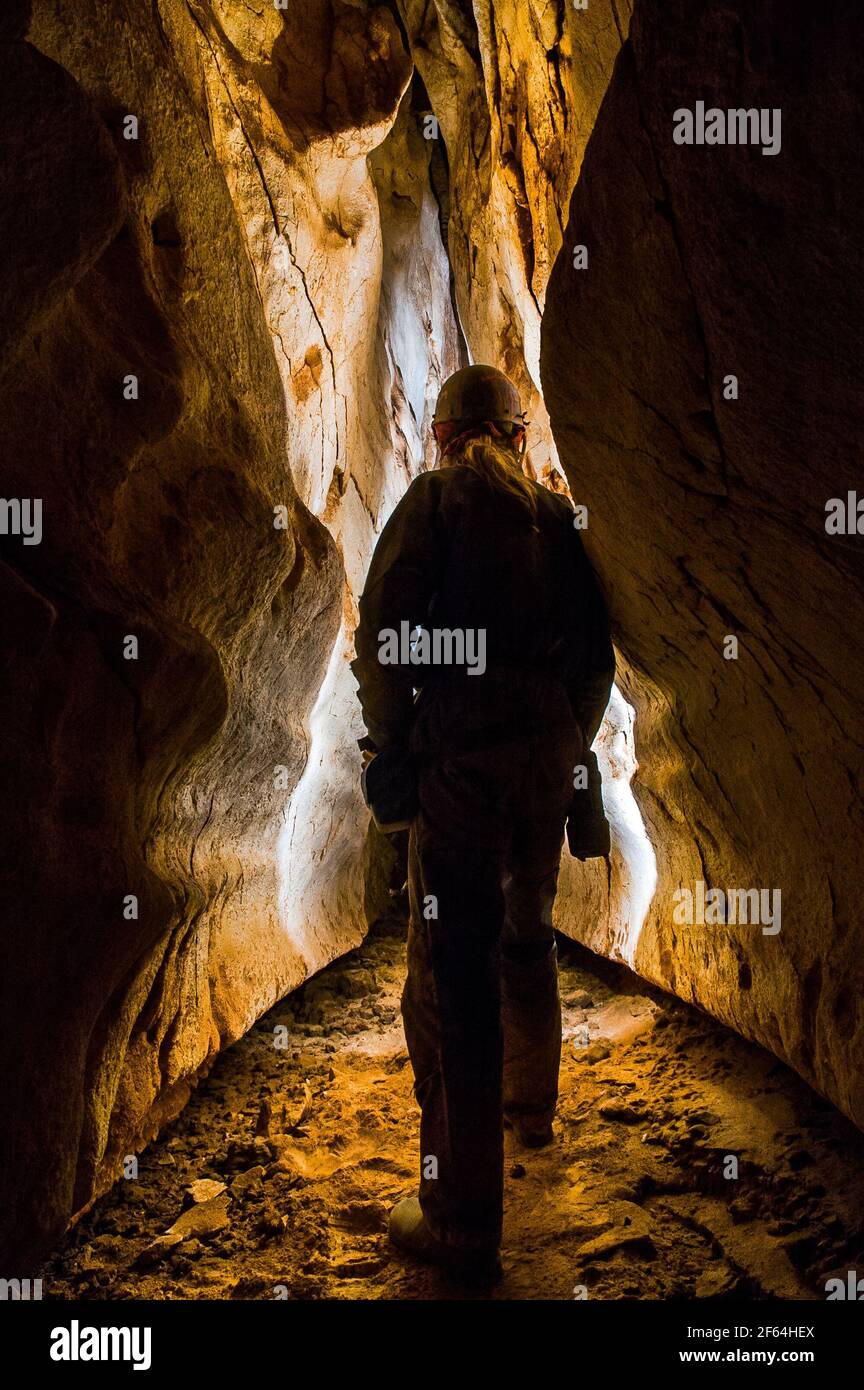 Speleologist exploring a deep cave discovering new underground passage ...