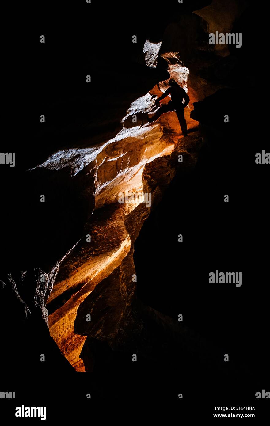 Climbing speleologist exploring a deep cave discovering new underground ...