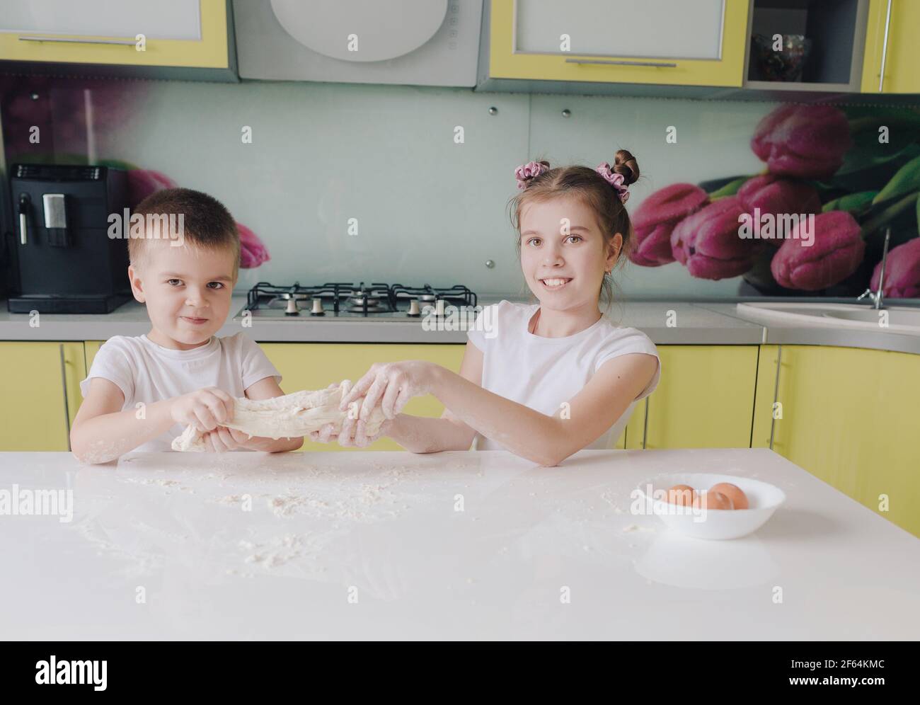 beautiful boy and girl stretch dough in the kitchen mess around and ...