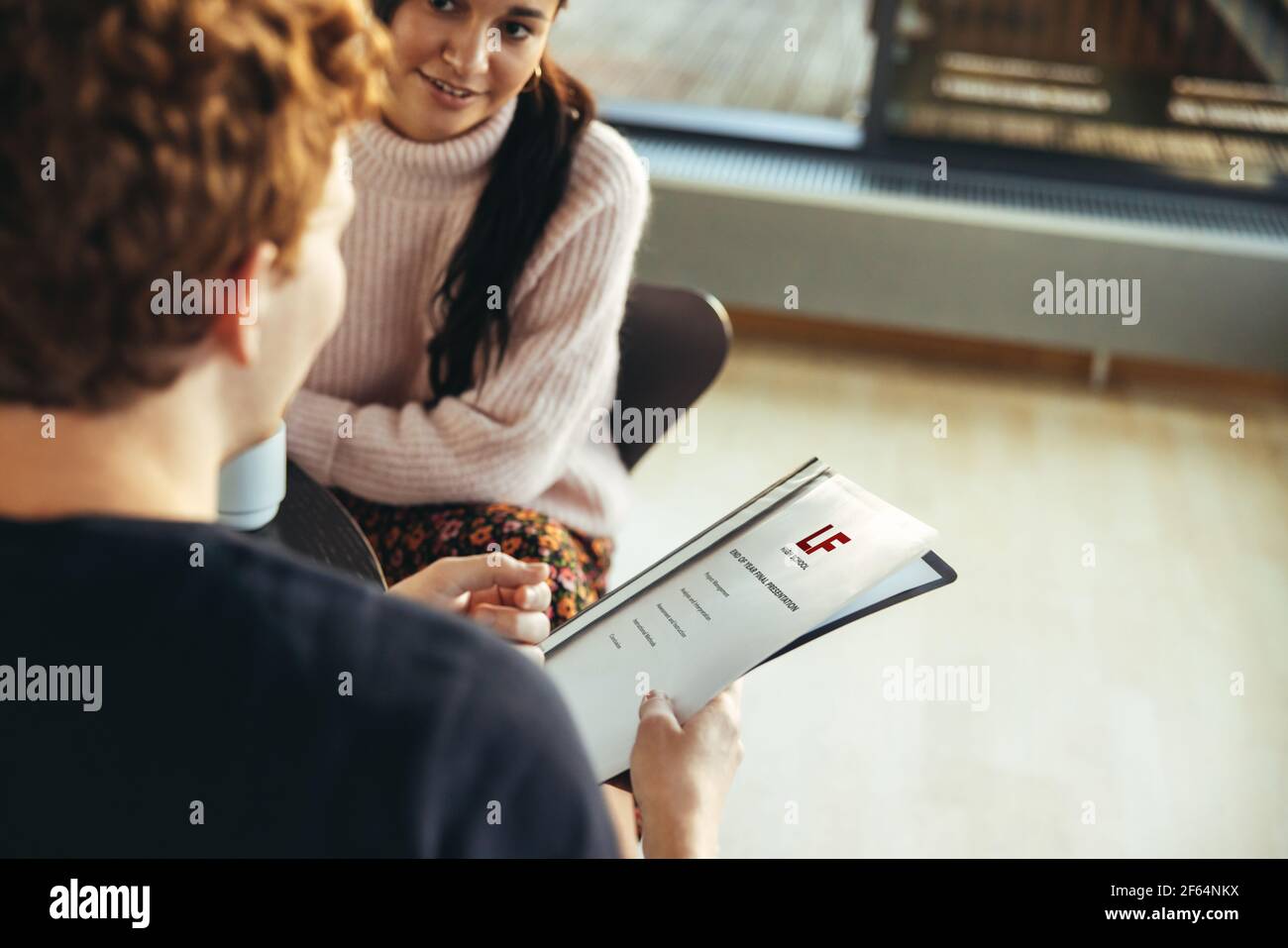 Two students discussing project file in college. Girl and boy studying ...