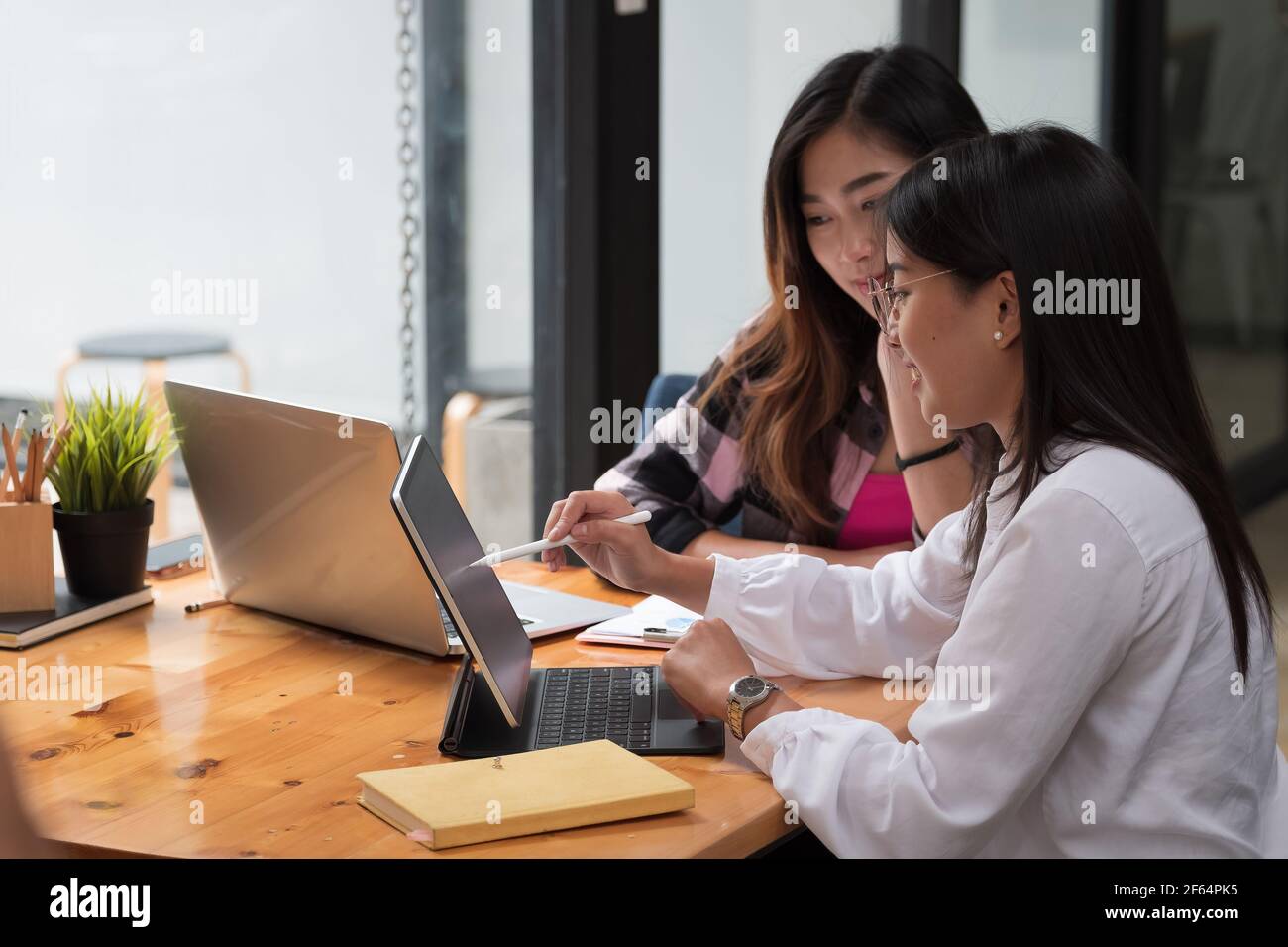 Shot of two young asian female students consulting on their group ...