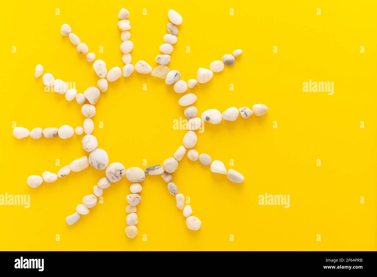 Abstract sun from sea pebbles on a yellow background, copy space ...