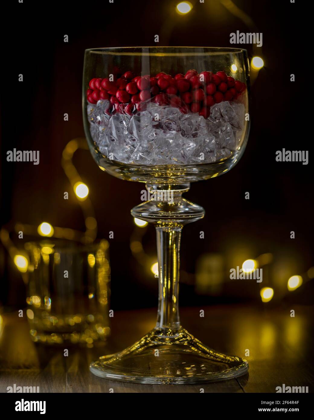 An elegant glass vase is filled with a layer of ice cubes and a layer ...