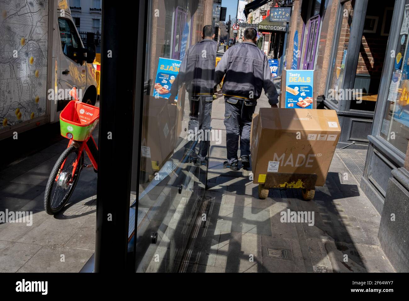 A discarded Lime rental bike stands in a bus shelter as delivery man ...