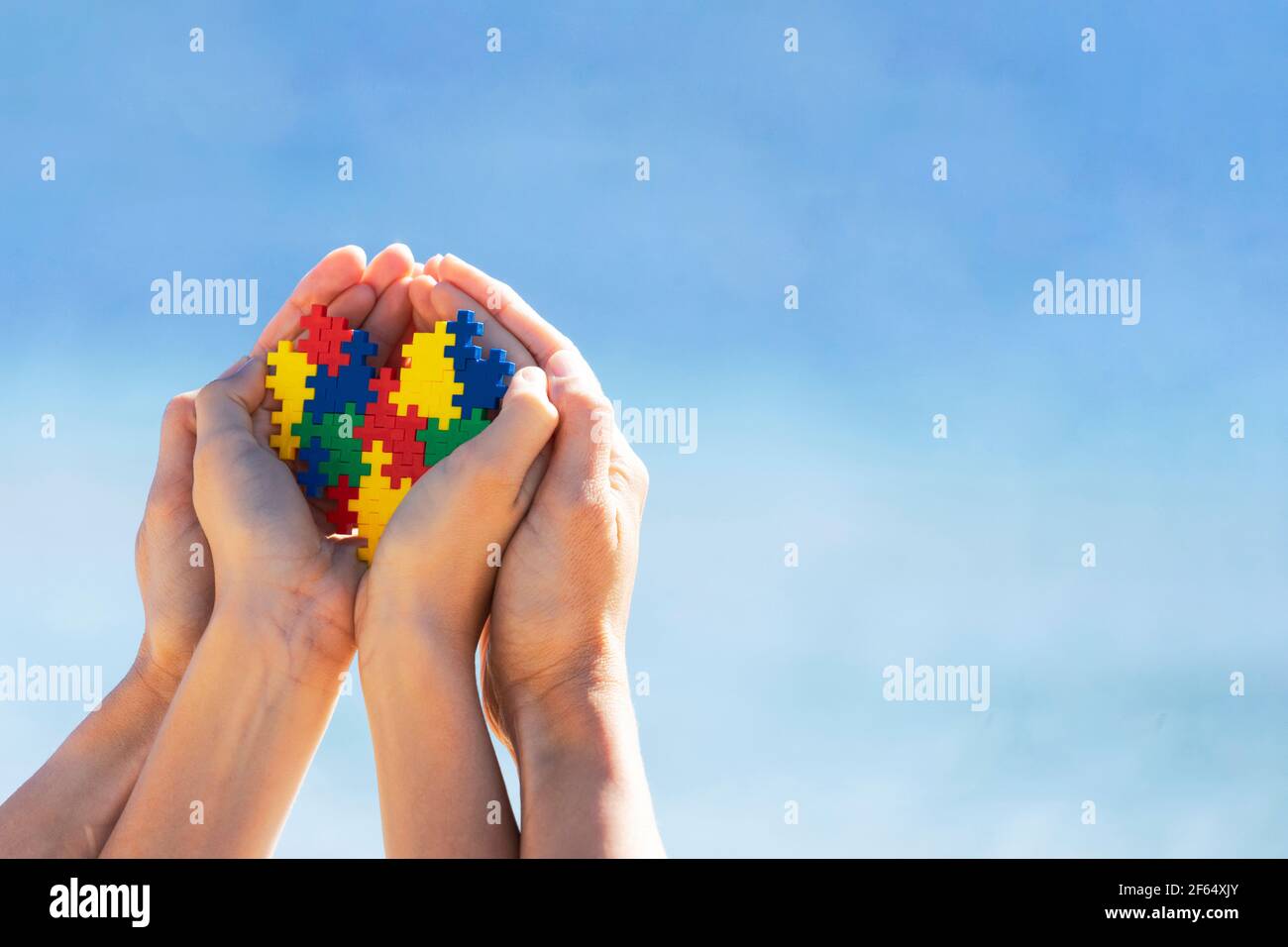Autistic kid hands with multicolored puzzle heart supported by mother ...