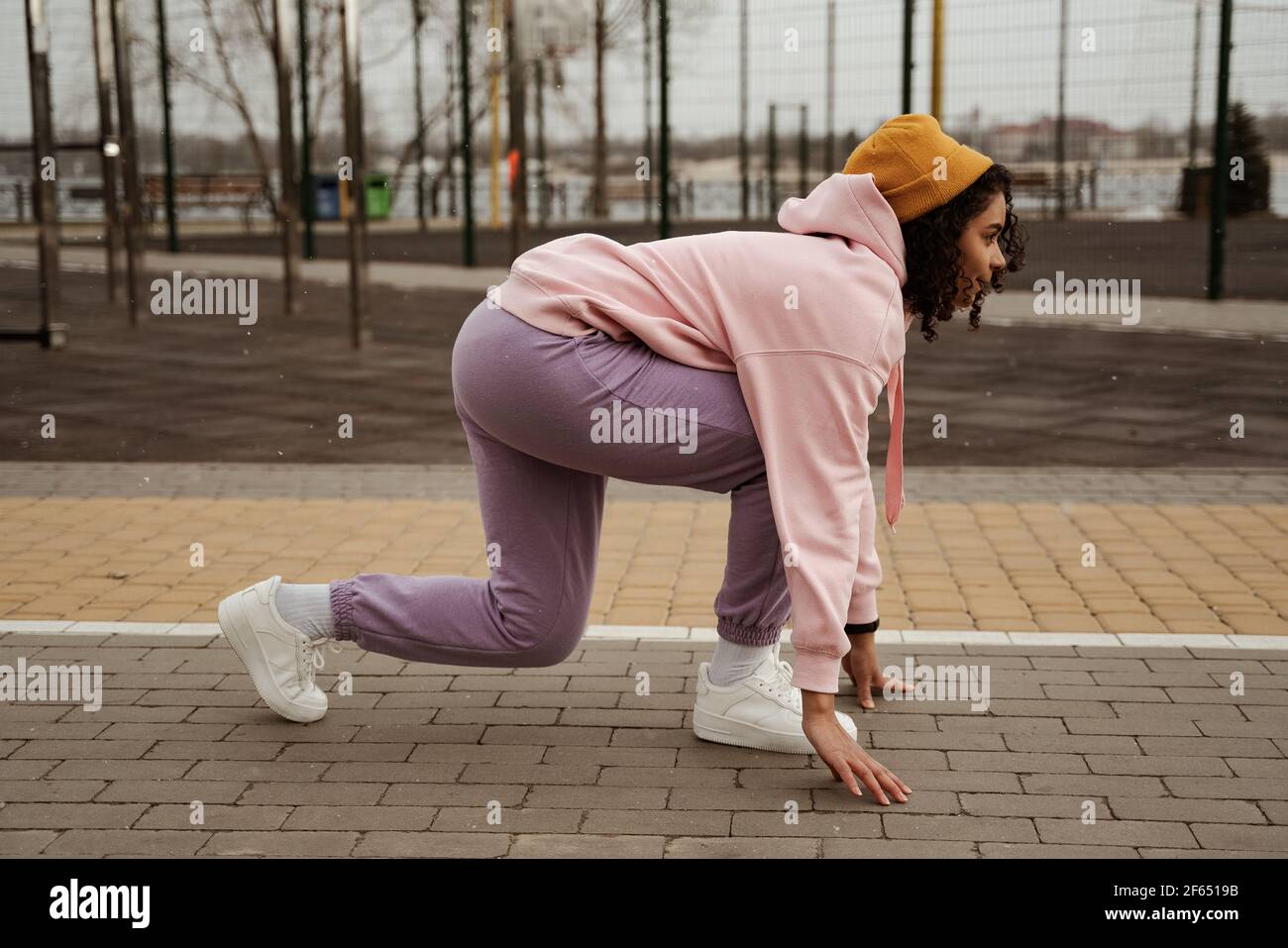 side view of african american jogger standing in low start position ...