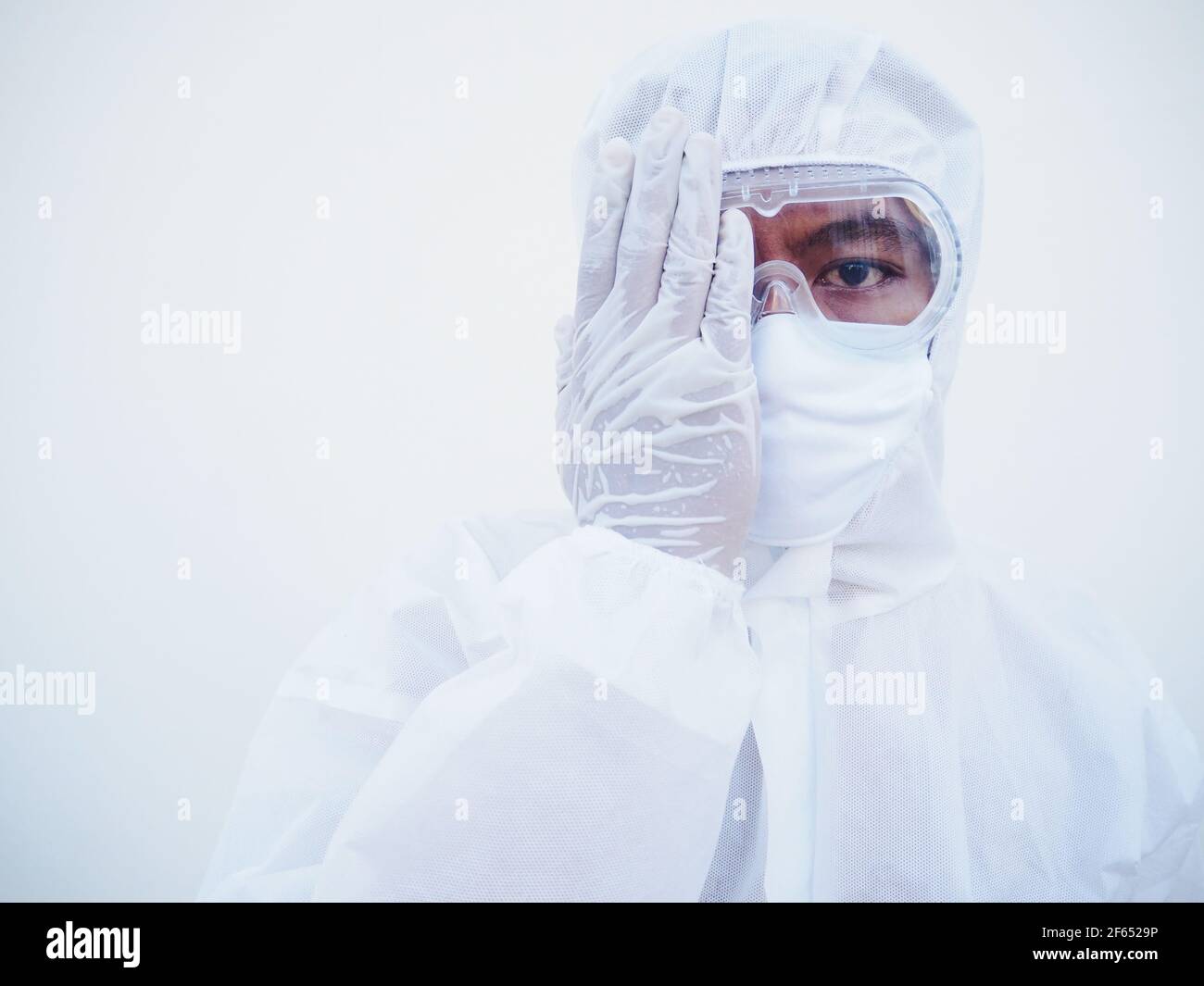 Shot of asian doctor or scientist in PPE suite uniform covering one eye ...