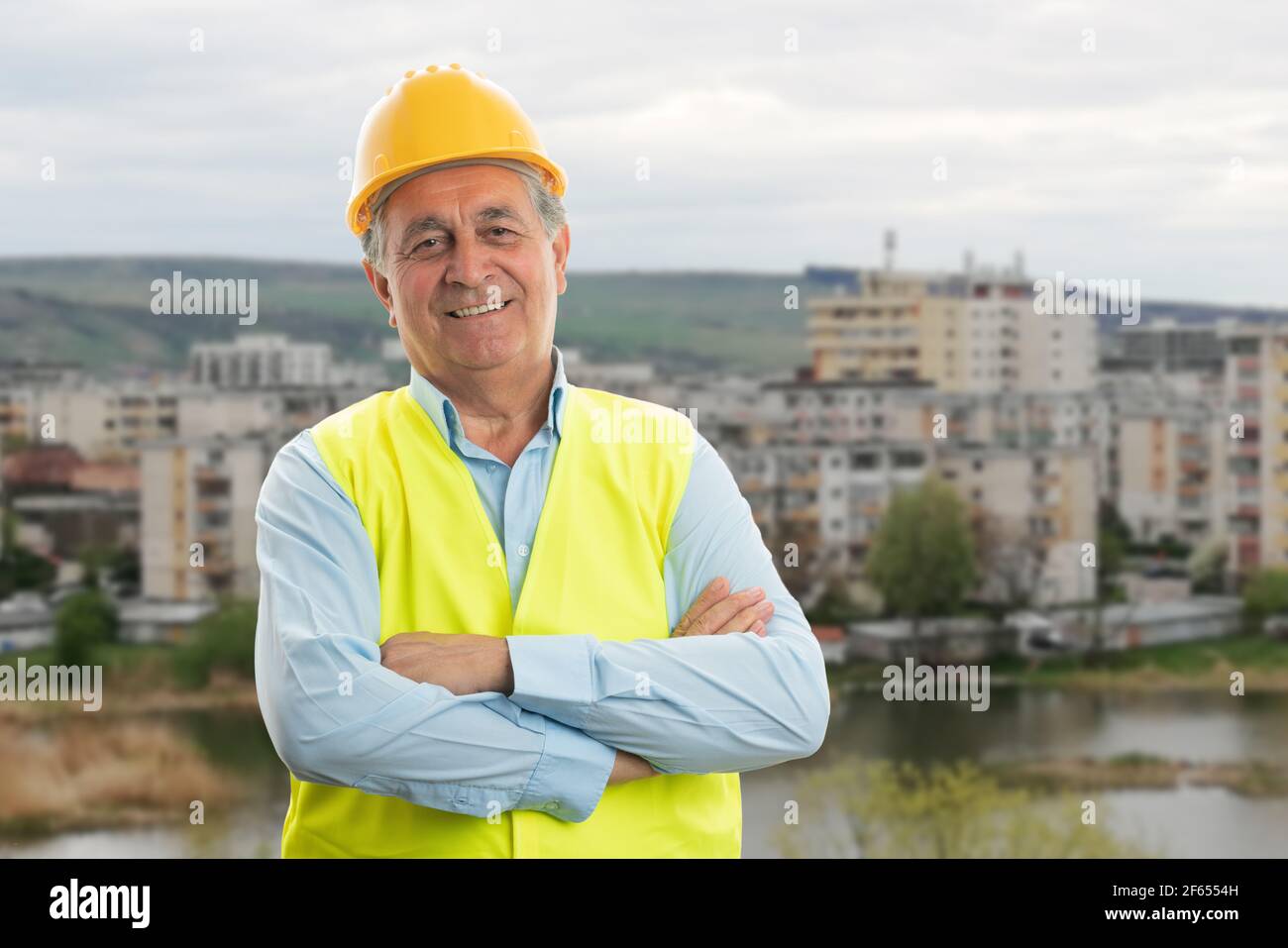 Friendly old male construction worker wearing trades clothing vest and ...