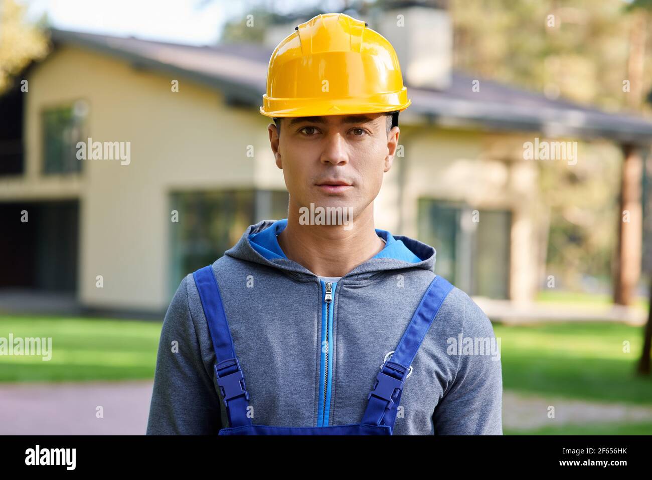 Portrait of handsome young male engineer in hard hat looking at camera ...