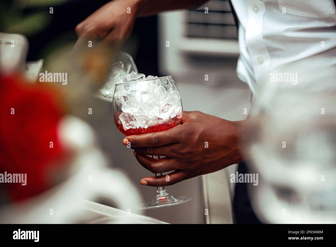 A man's hand in a white shirt putting ice into a glass Stock Photo - Alamy