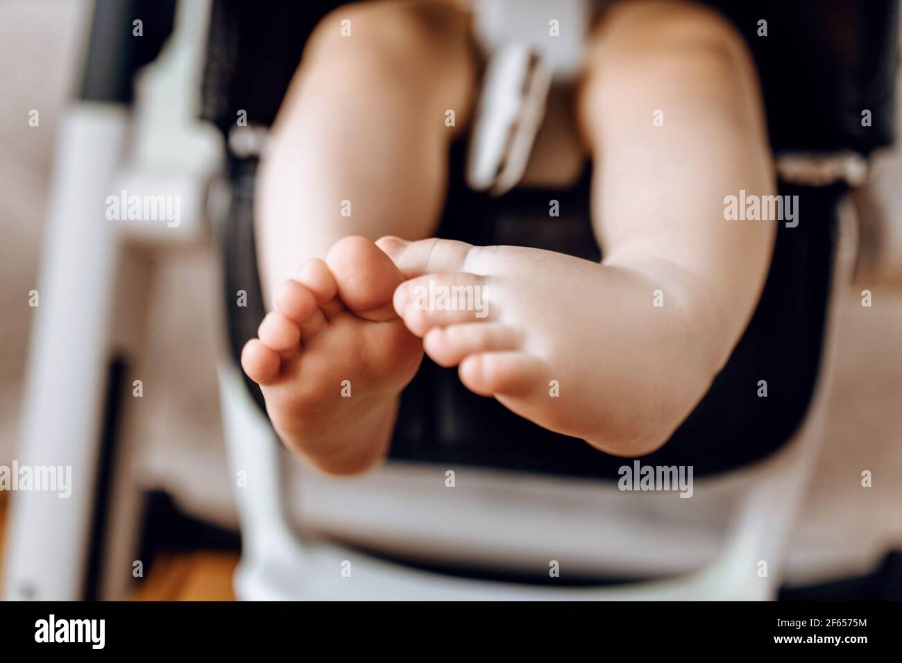 Little baby feet on the highchair, little toddler sitting on the chair ...