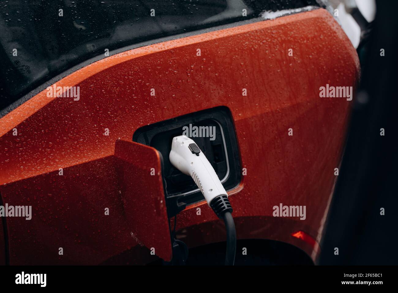Electric car with power cable supply plugged in Stock Photo - Alamy