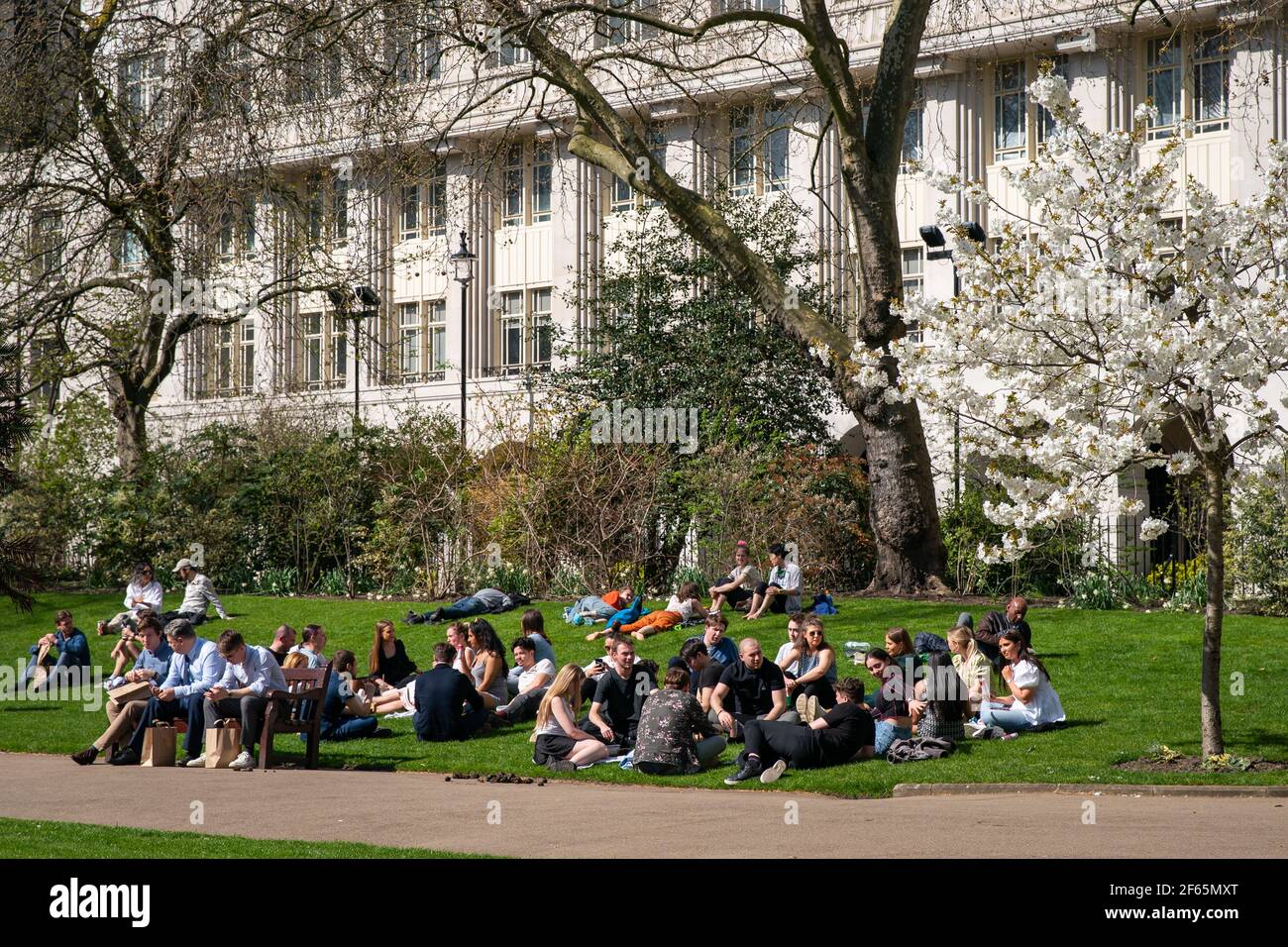 A large group of people relax in the sun at the Victoria Embankment ...
