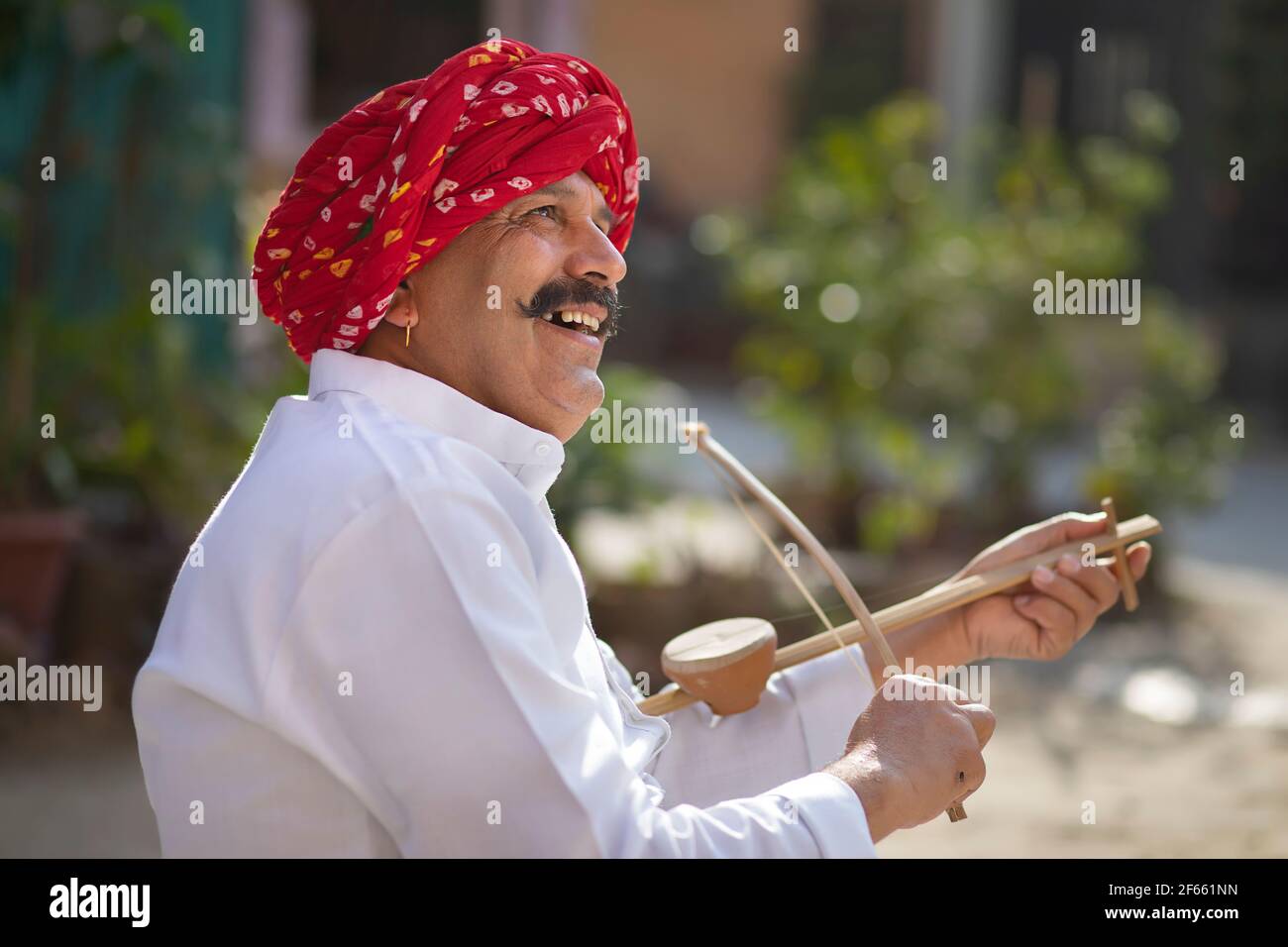 A HAPPY ADULT MAN SITTING AND PLAYING EKTARA INSTRUMENT Stock Photo - Alamy