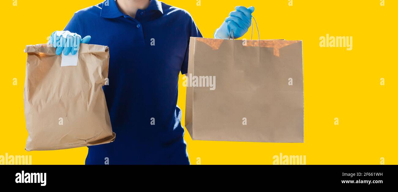 delivery man carrying paper bag with food products isolated over yellow ...
