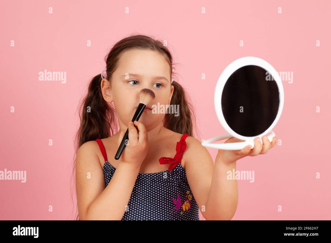 close-up portrait of a six-year-old girl with ponytails powdering her ...