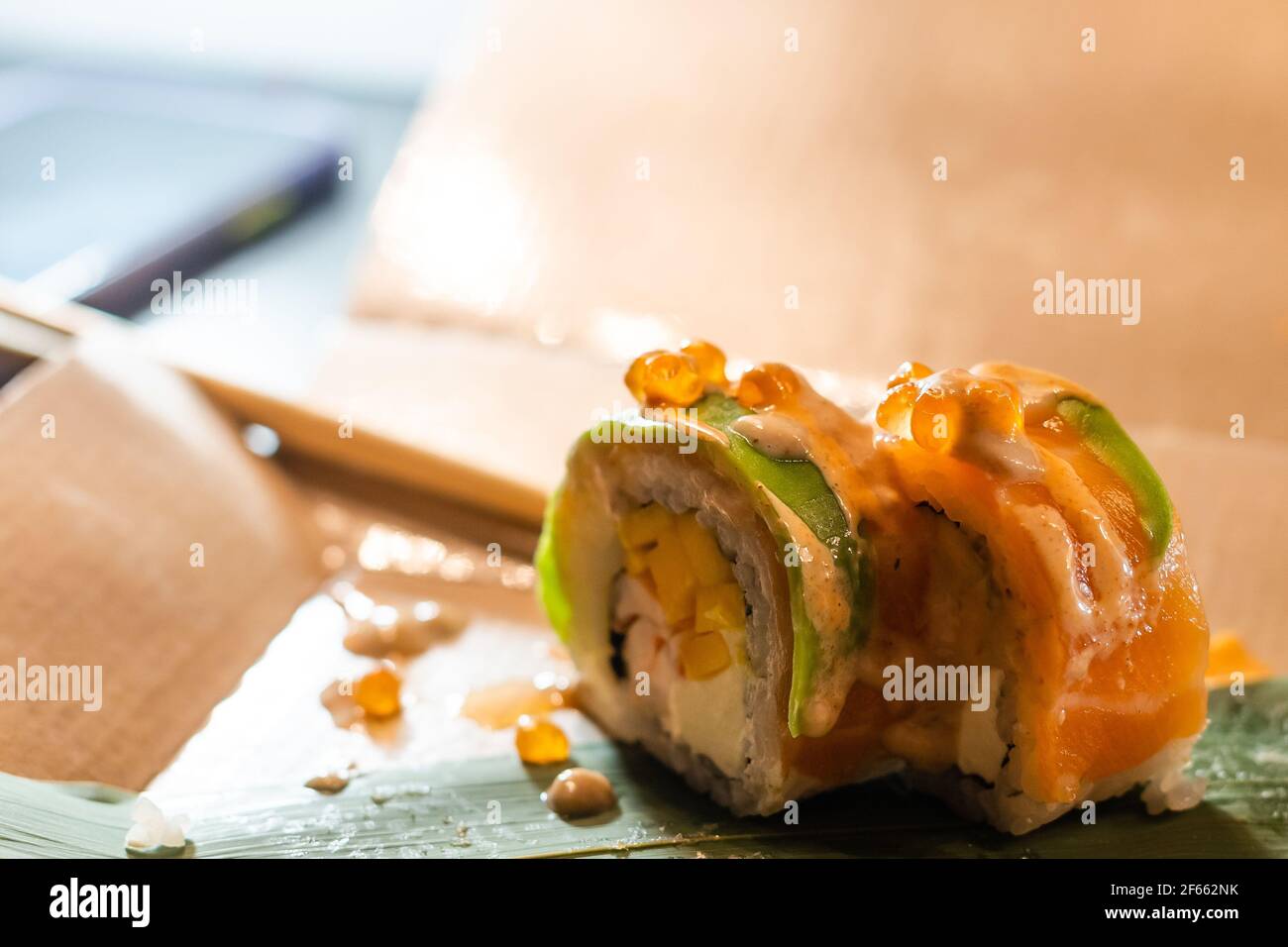 close up of chopsticks taking portion of sushi roll on the table ...