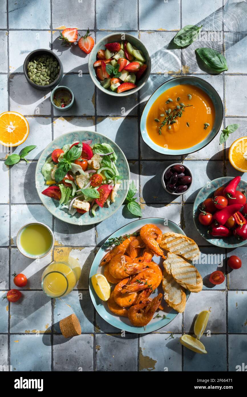 Mediterranean dishes at tiles table: seafood shrimps, vegetable salad ...