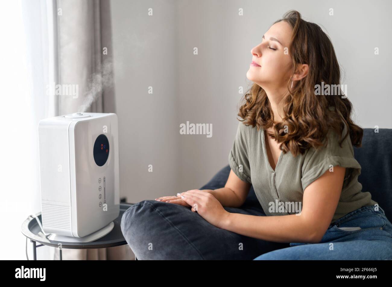 Fresh and wellness young woman using air humidifier at cozy apartment ...
