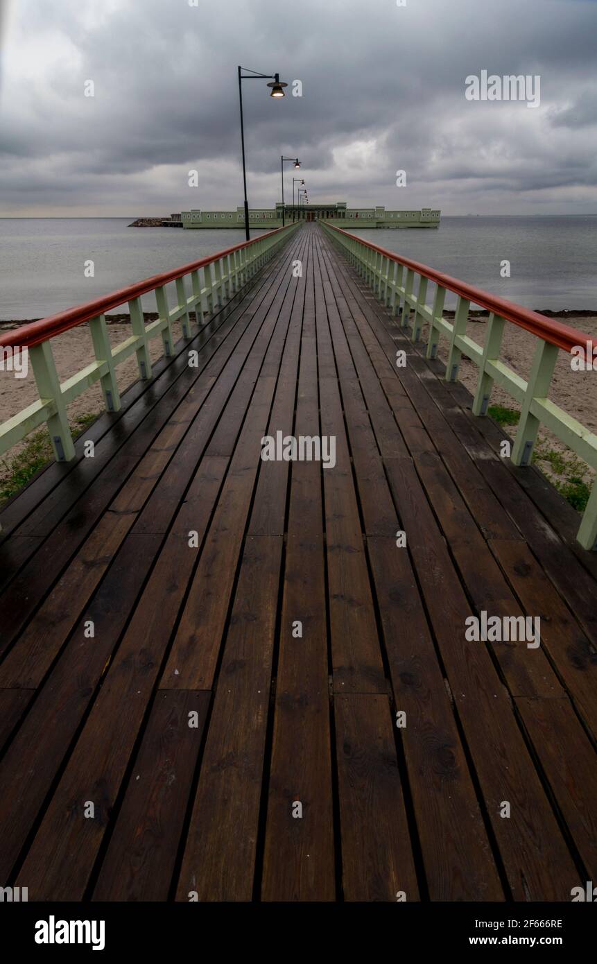 A long pier / jetty with wooden plank flooring and painted hand rails ...
