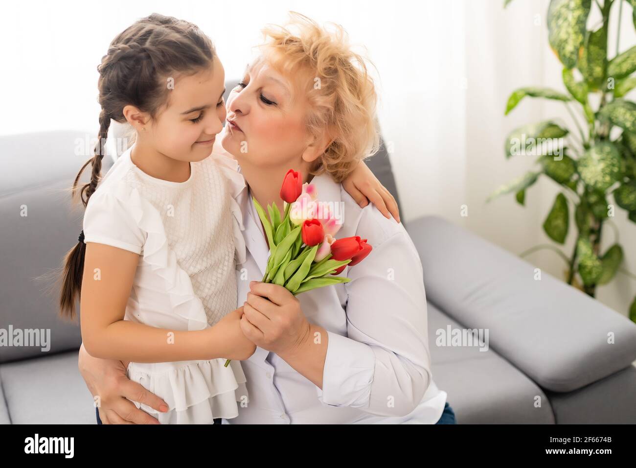 Sincere cute little granddaughter strong cuddling and kissing in cheek ...