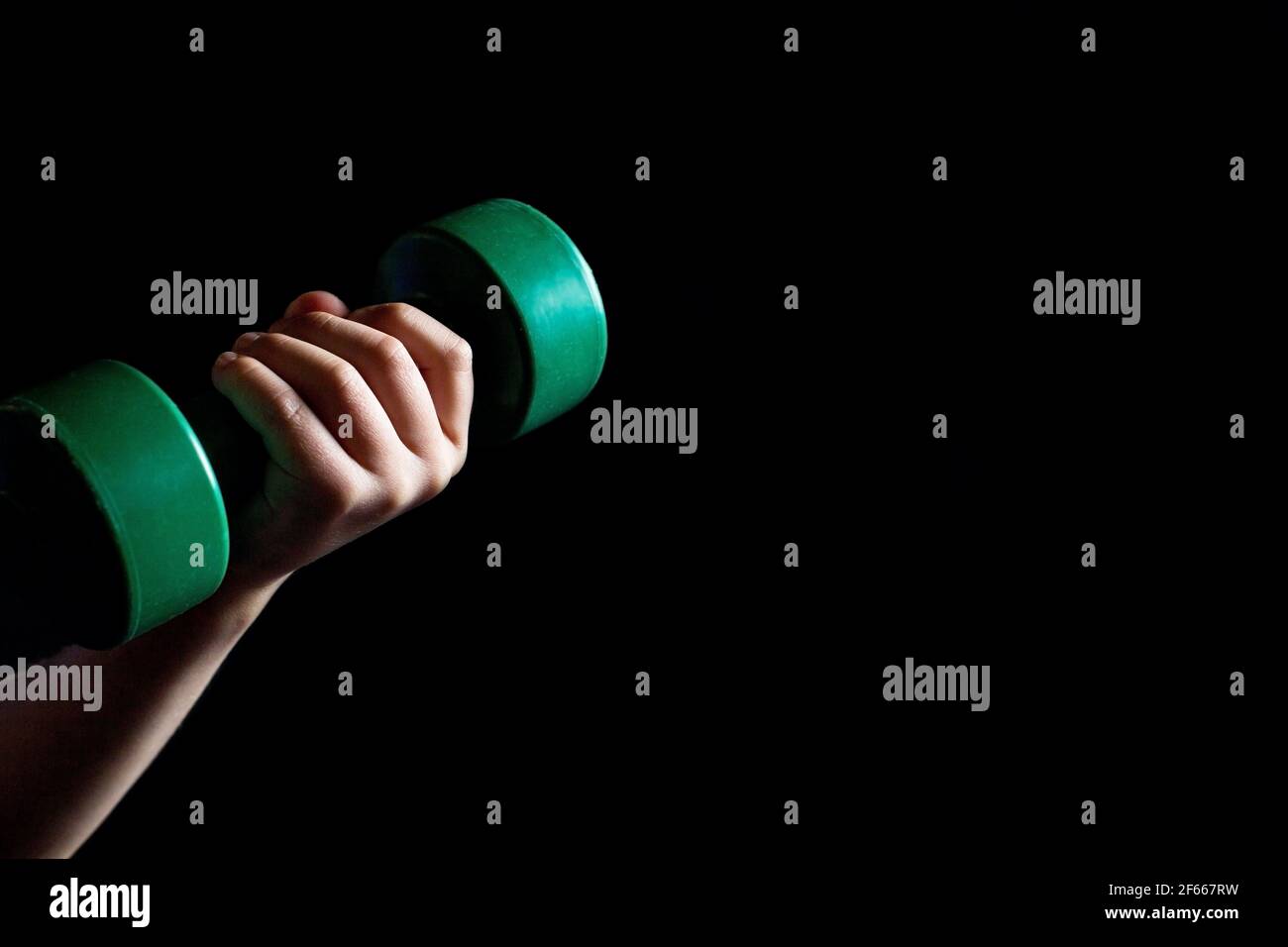 Hand holding green small dumbbell isolated on black background with ...