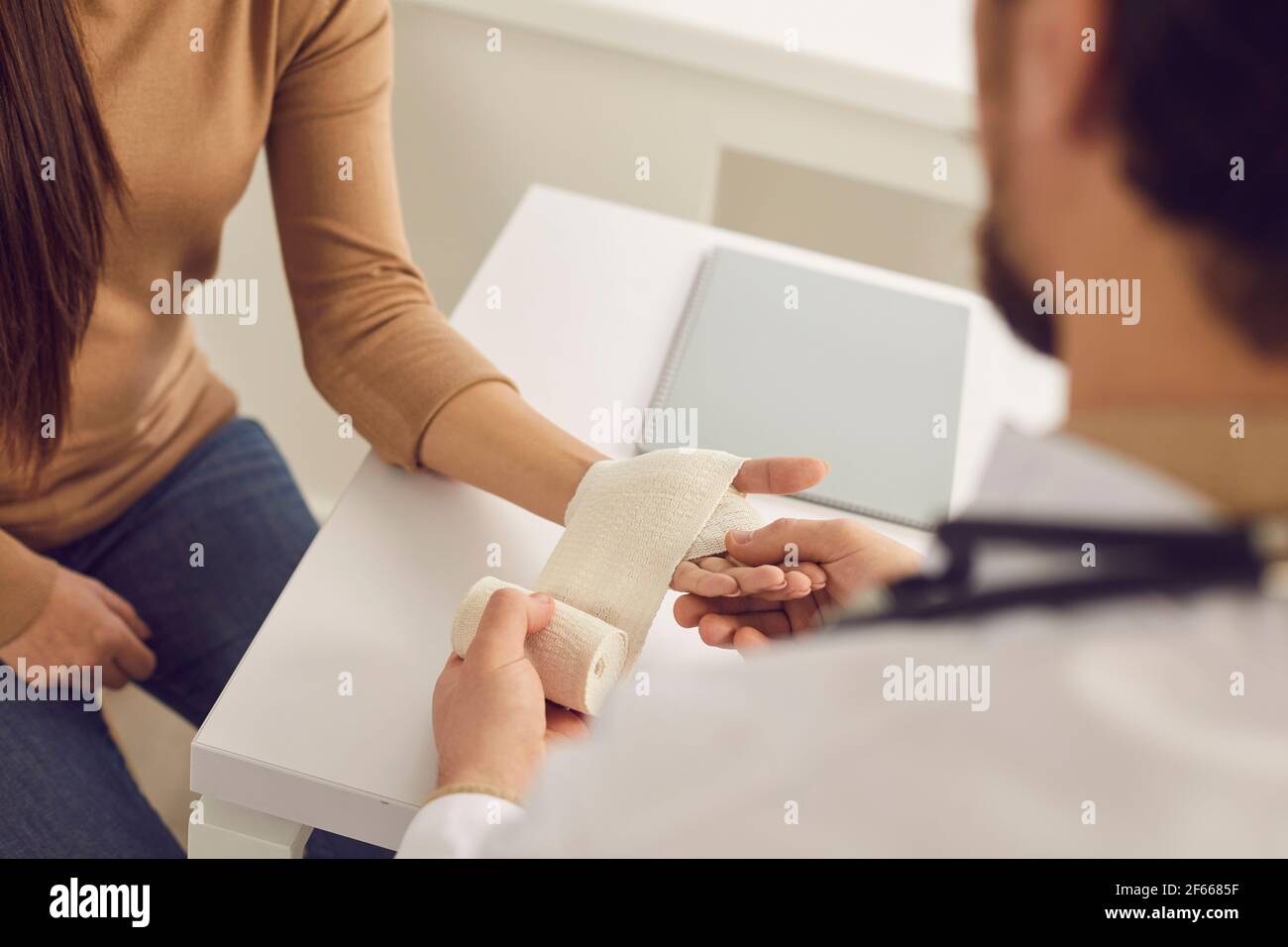Traumatologist providing first aid to woman and wrapping her injured ...