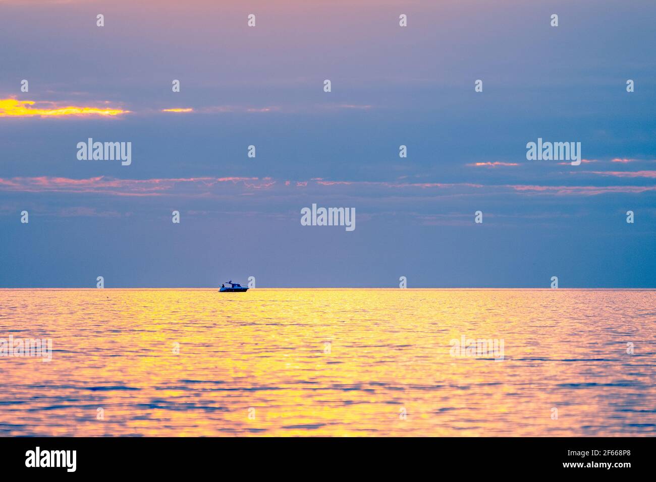 Ship sailing alone at sea at sunset Stock Photo - Alamy