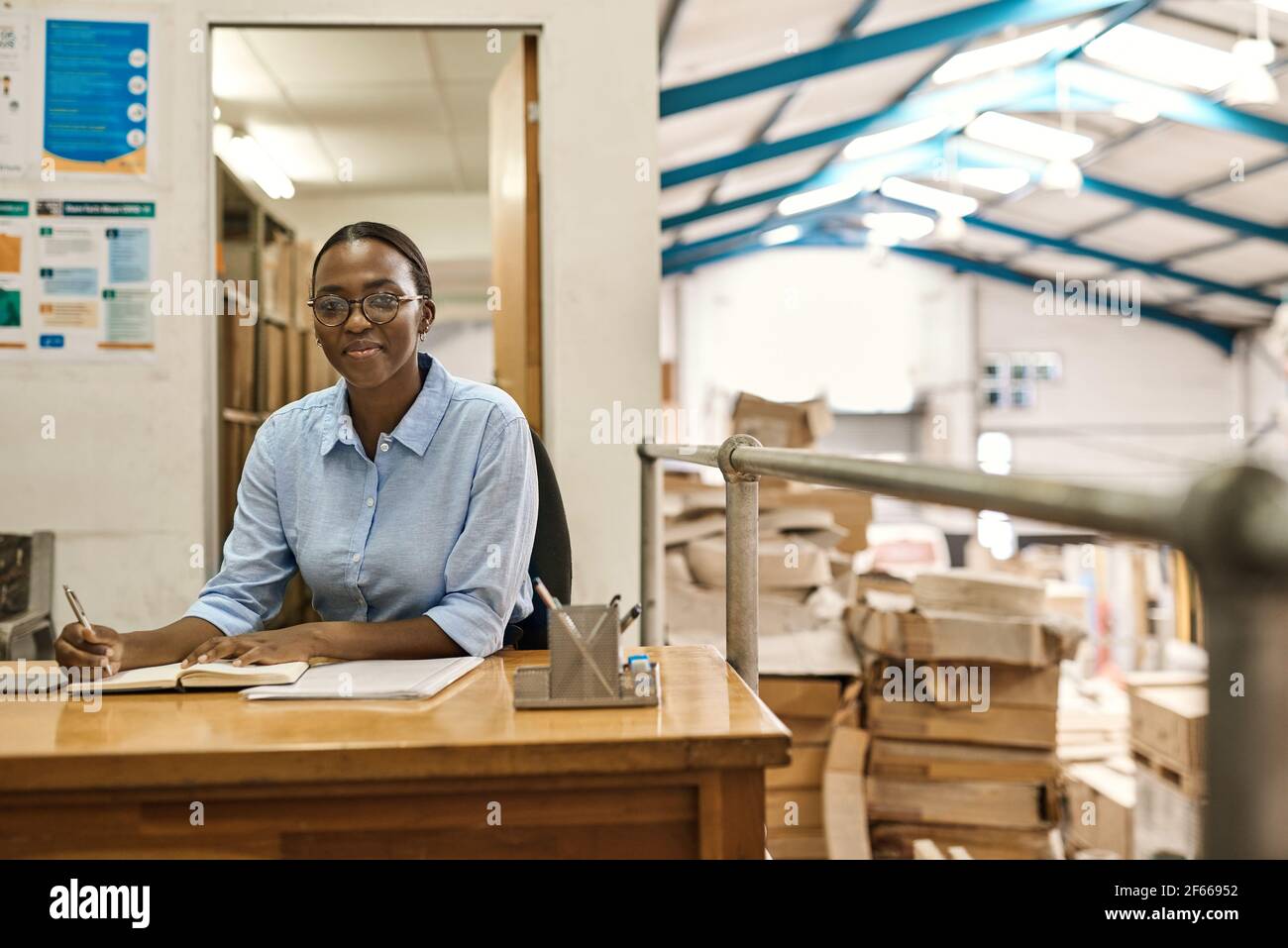 Smiling young African woman working at her desk in a warehouse Stock ...