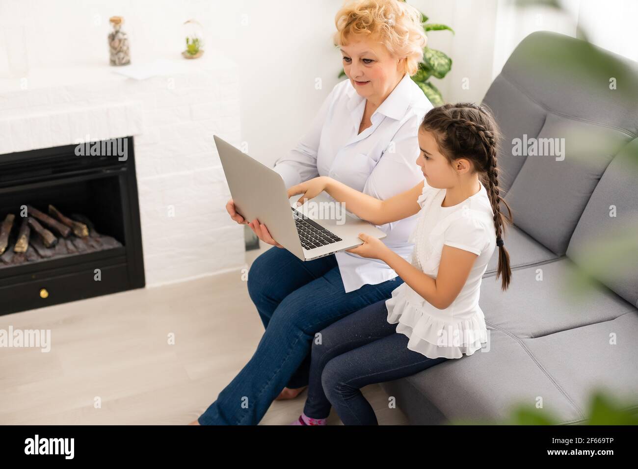 modern grandmother teaching grandchild how to use laptop computer at ...
