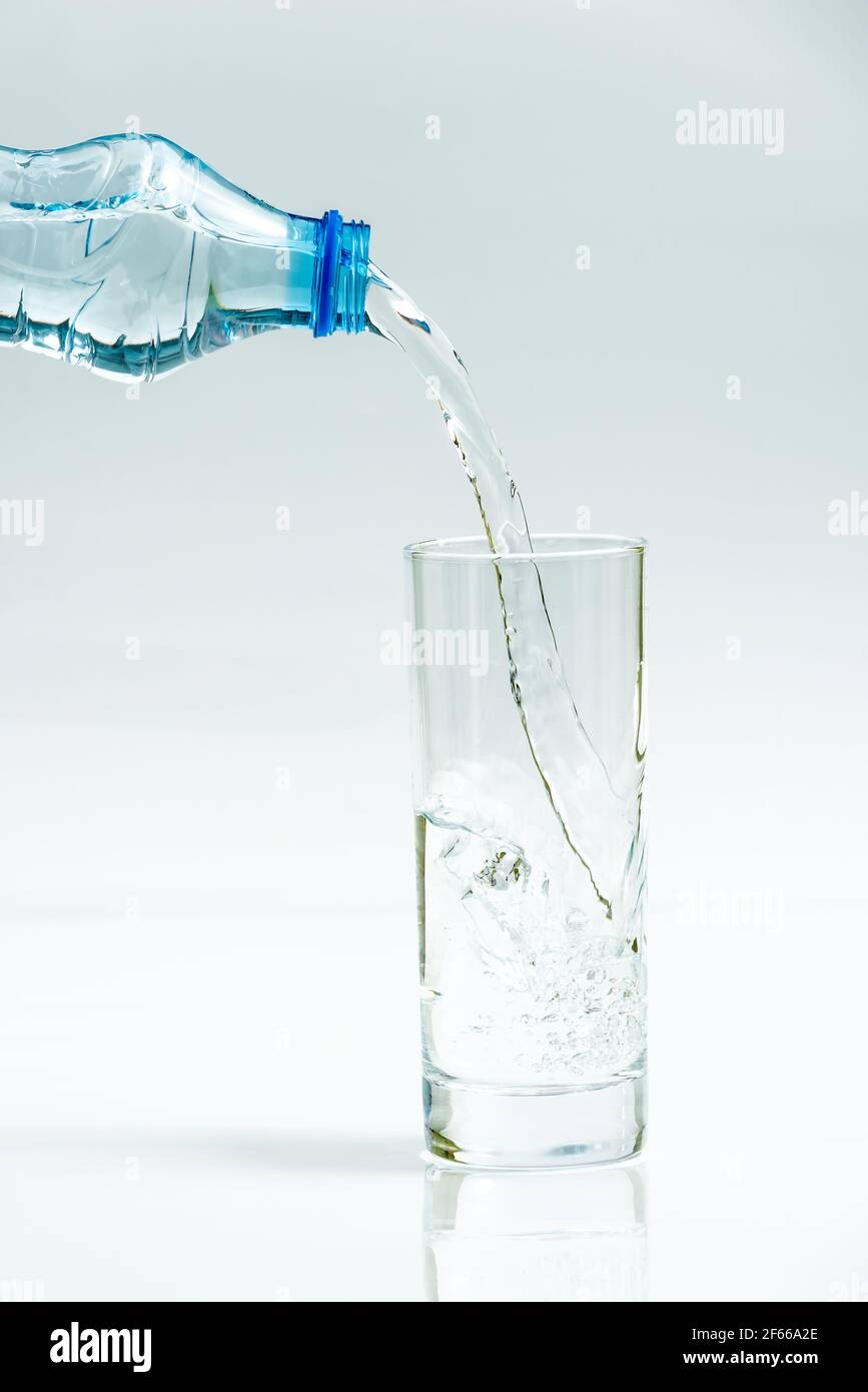 Water bottle pour water to glass on white background Stock Photo - Alamy