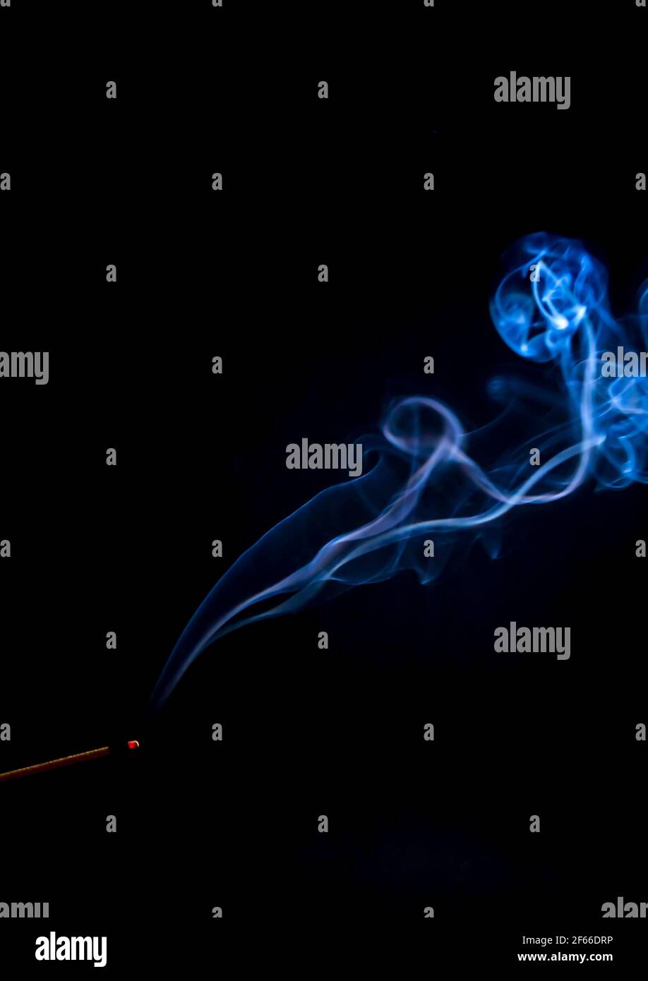 Incense stick lit and fuming on black background Stock Photo - Alamy