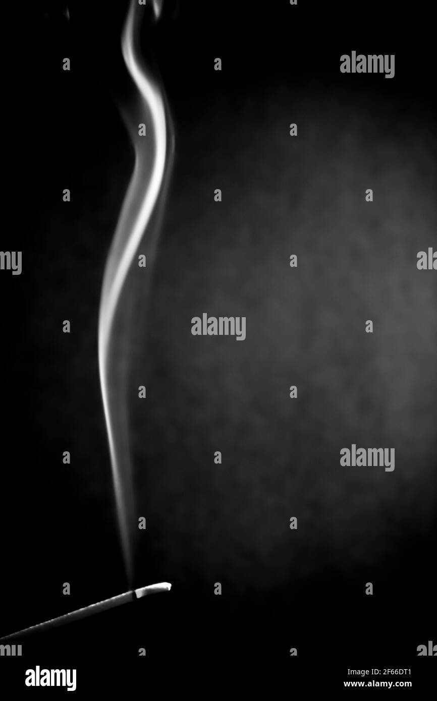 Incense stick lit and fuming on black background Stock Photo - Alamy