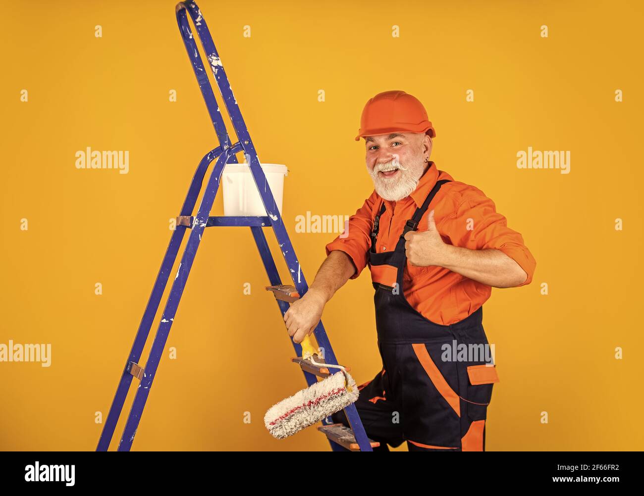man in working clothes painting wall in empty room. painter in overall ...