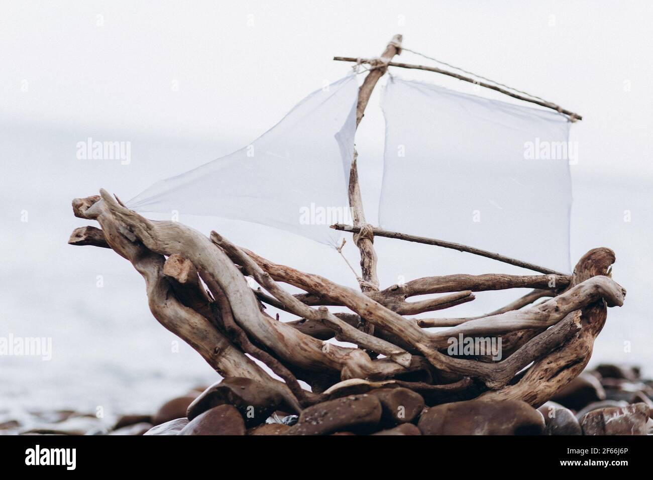 Decorative ship made of branches and roots with a sail on the seashore ...