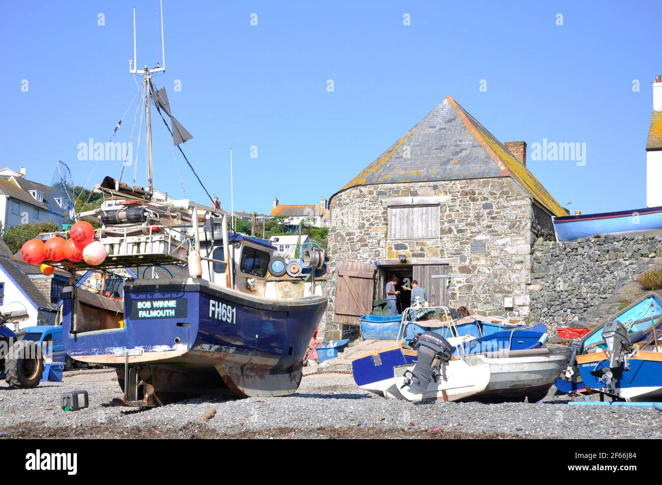 Fishing boats and fishermen's net store in Cadgwith cove harbour ...
